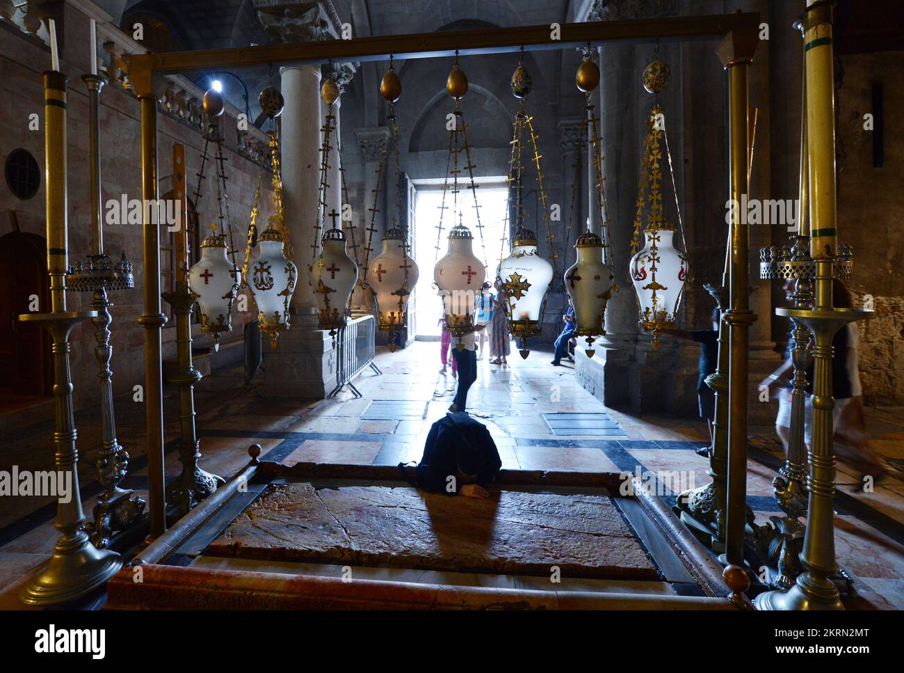 A woman kneeling and praying at the Stone of Anointing inside the ...