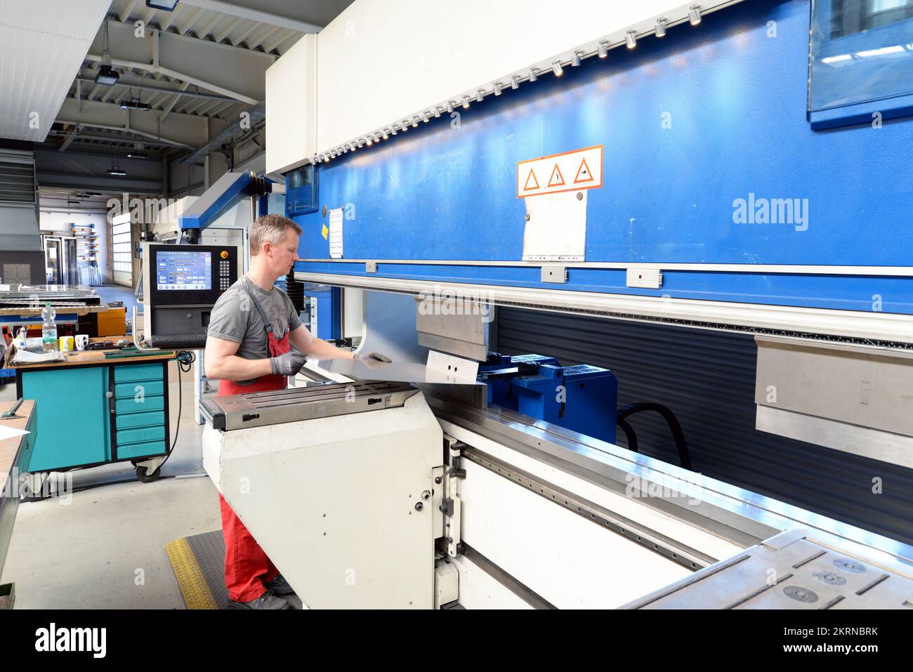 employee operates bending machine in a metalworking company - bending ...