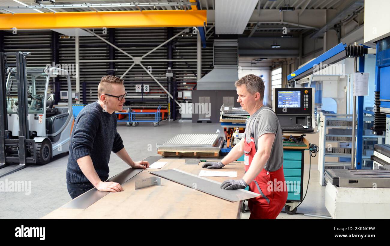 teamwork in the metal industry - two workers and engineer talking about ...
