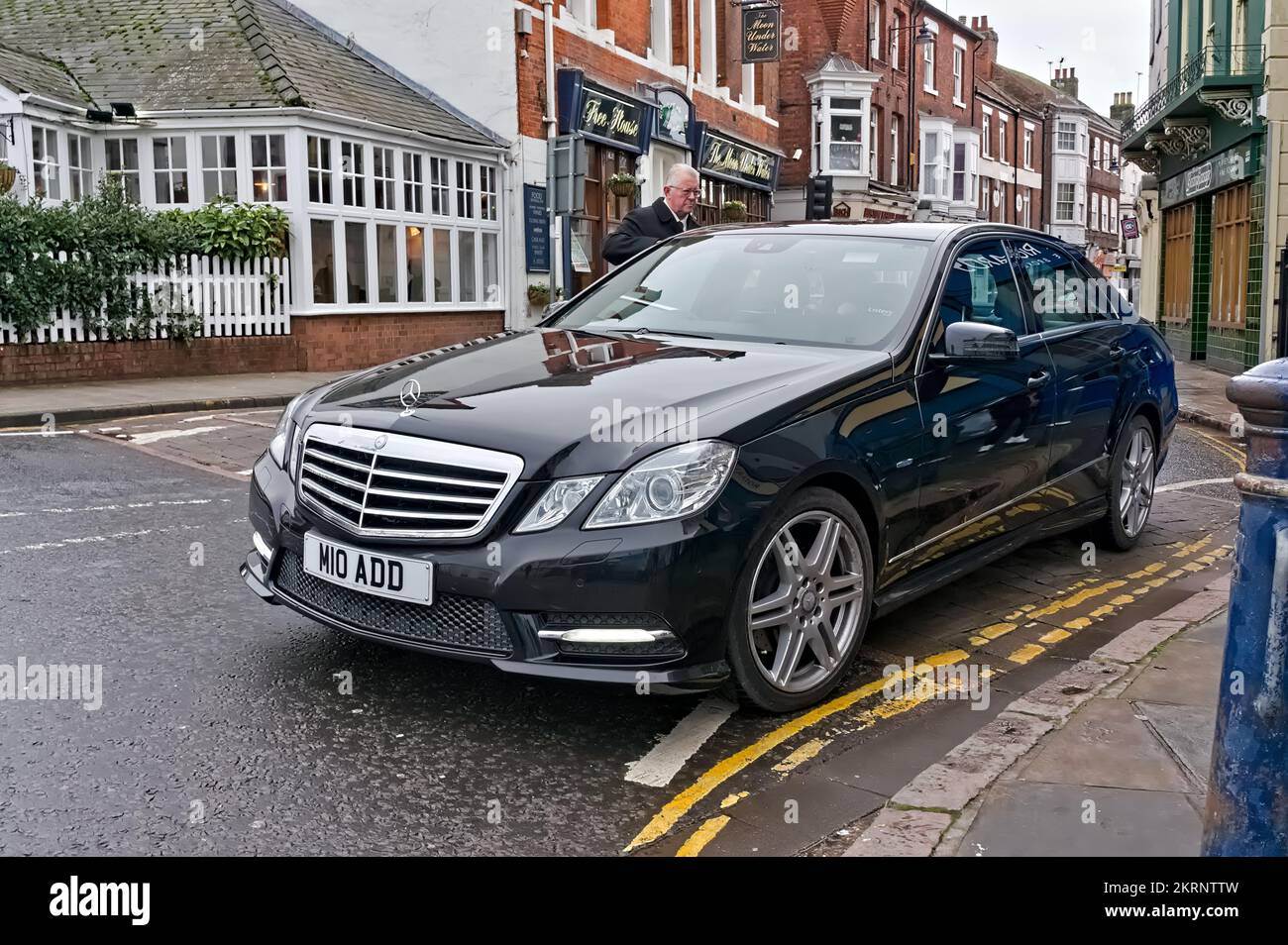 Modern Mercedes Benz funeral car with driver parked on High street in ...
