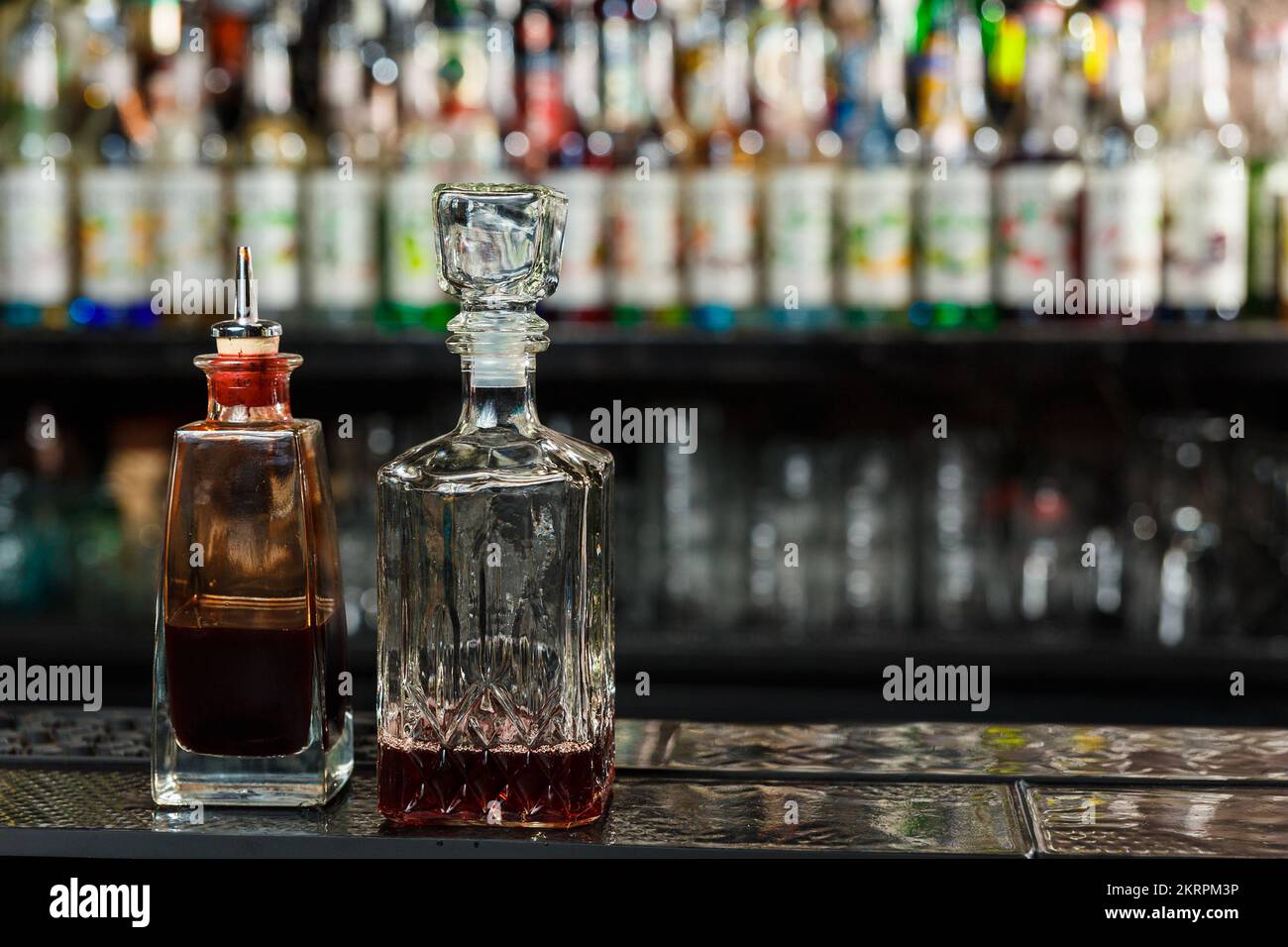 decanters with angostura and sweet liqueur stand in the semi-darkness ...