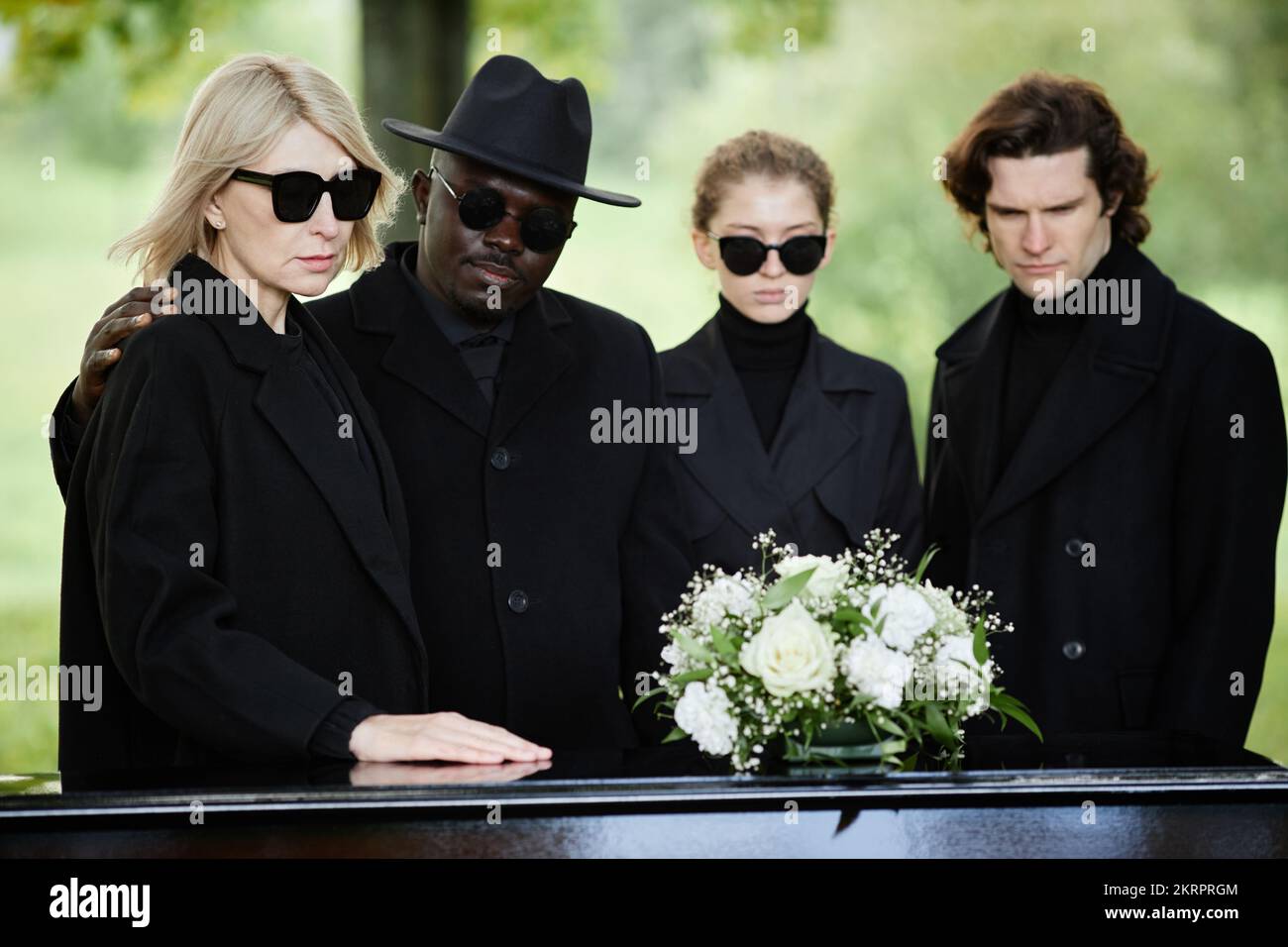 Group of people standing by coffin at outdoor funeral ceremony all ...