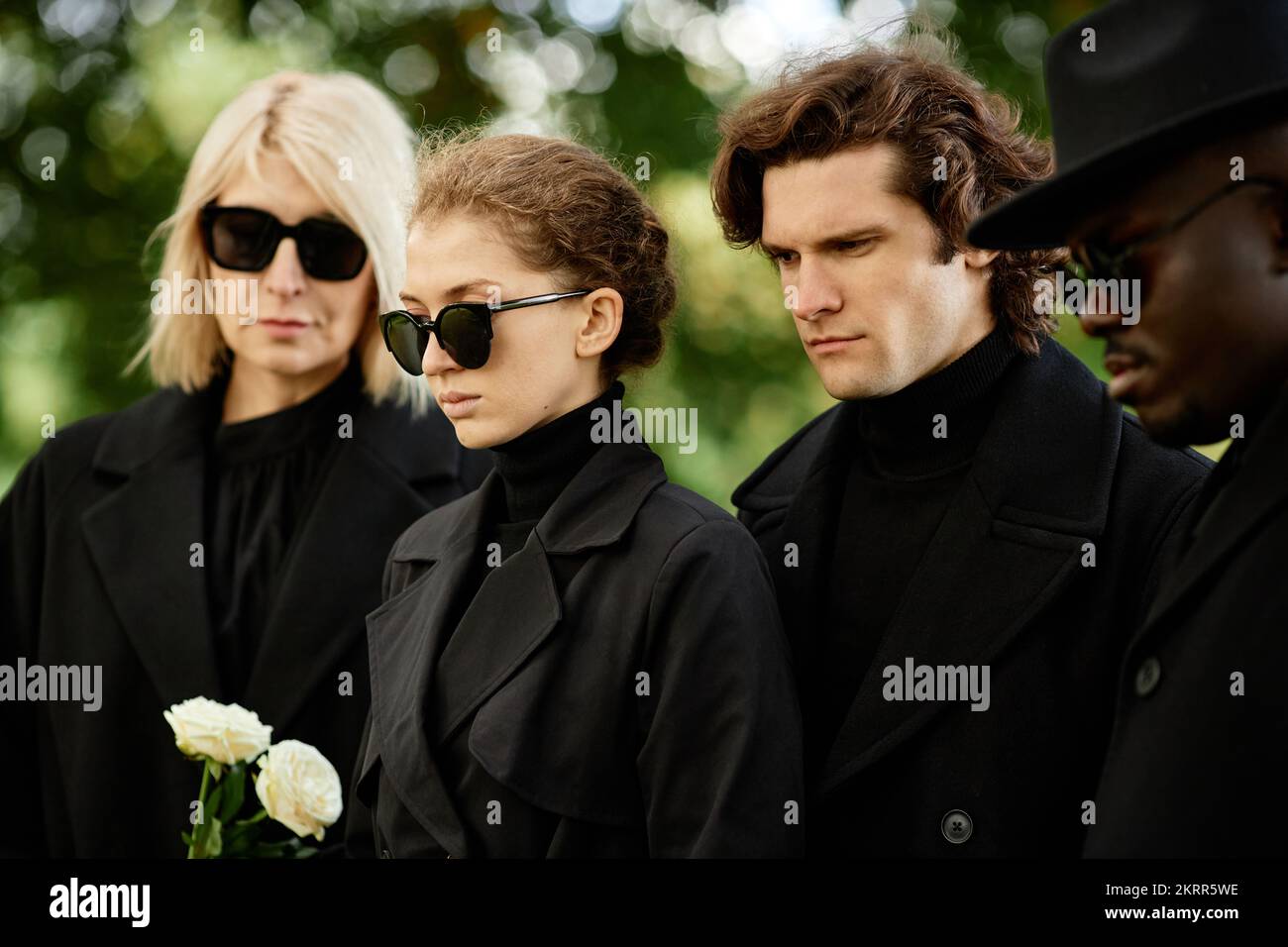 Group of people dressed in black standing at outdoor funeral ceremony ...