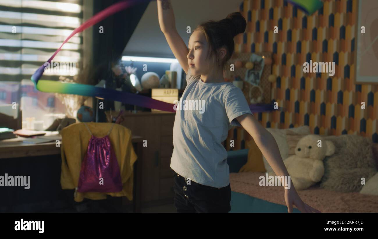 Young asian schoolgirl spins gymnastic ribbon around herself, and ...