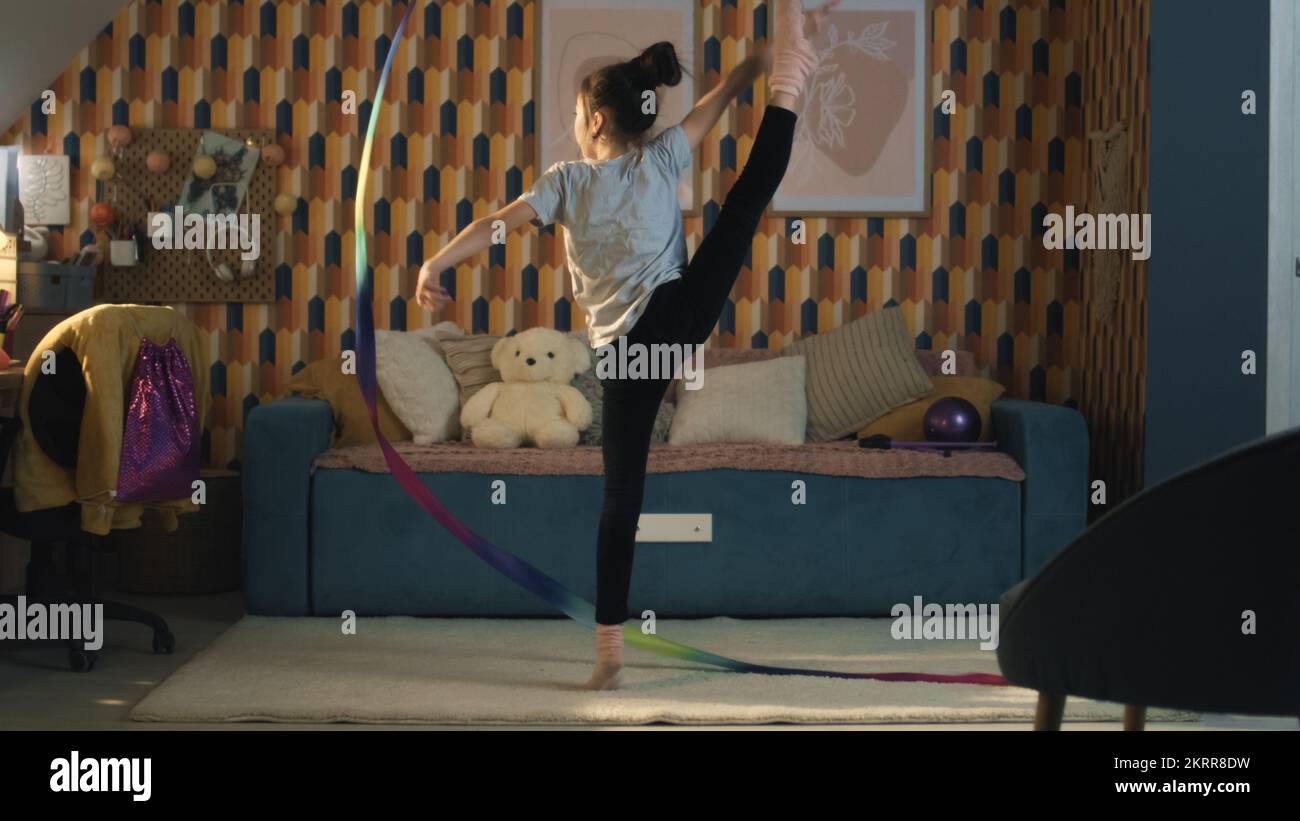 Young asian girl dances with gymnastic ribbon, showing vertical leg ...
