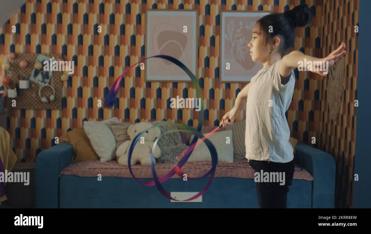Young asian schoolgirl dances with gymnastic ribbon, showing vertical ...