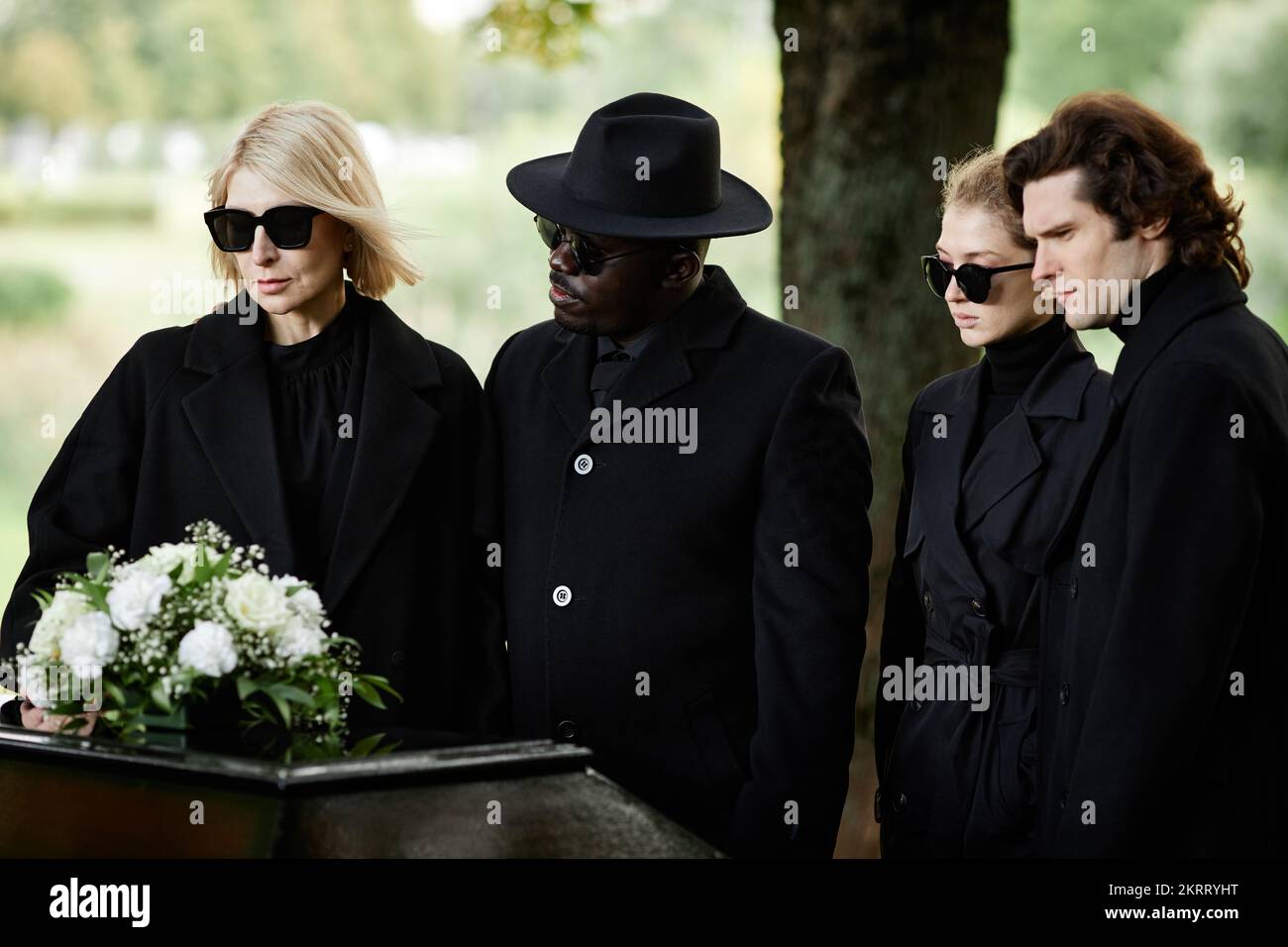 Group of people standing by coffin at funeral ceremony outdoors all ...