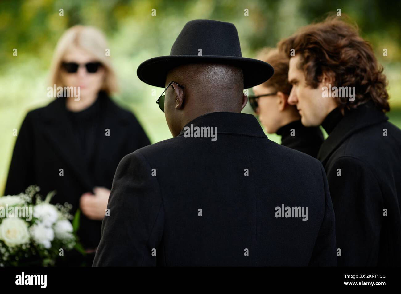 Back view of man wearing black standing at outdoor funeral ceremony ...
