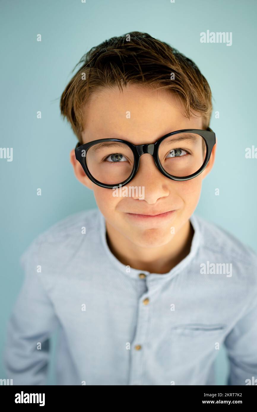 young cool boy with blue shirt, with big massive black glasses standing ...