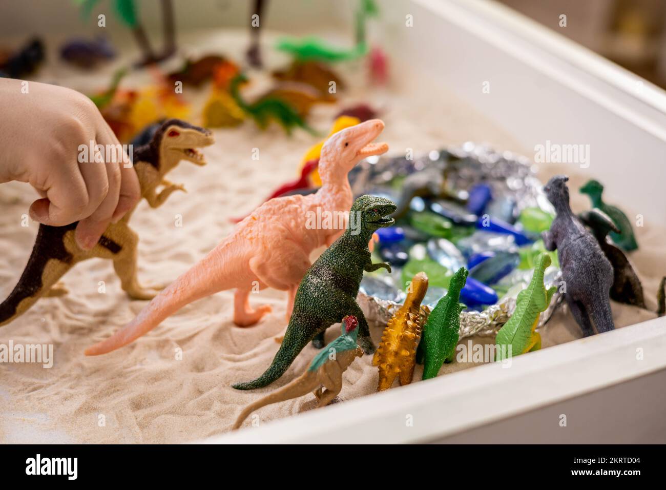 Closeup baby boy hands playing carnivorous and herbivorous dinosaurs ...