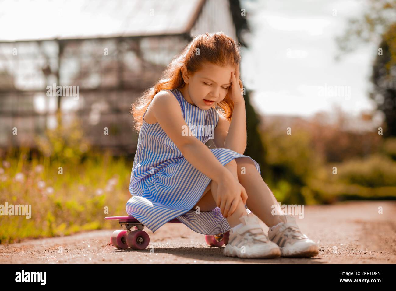 Ginger girl sitting on a skateboard and feeling tired Stock Photo - Alamy