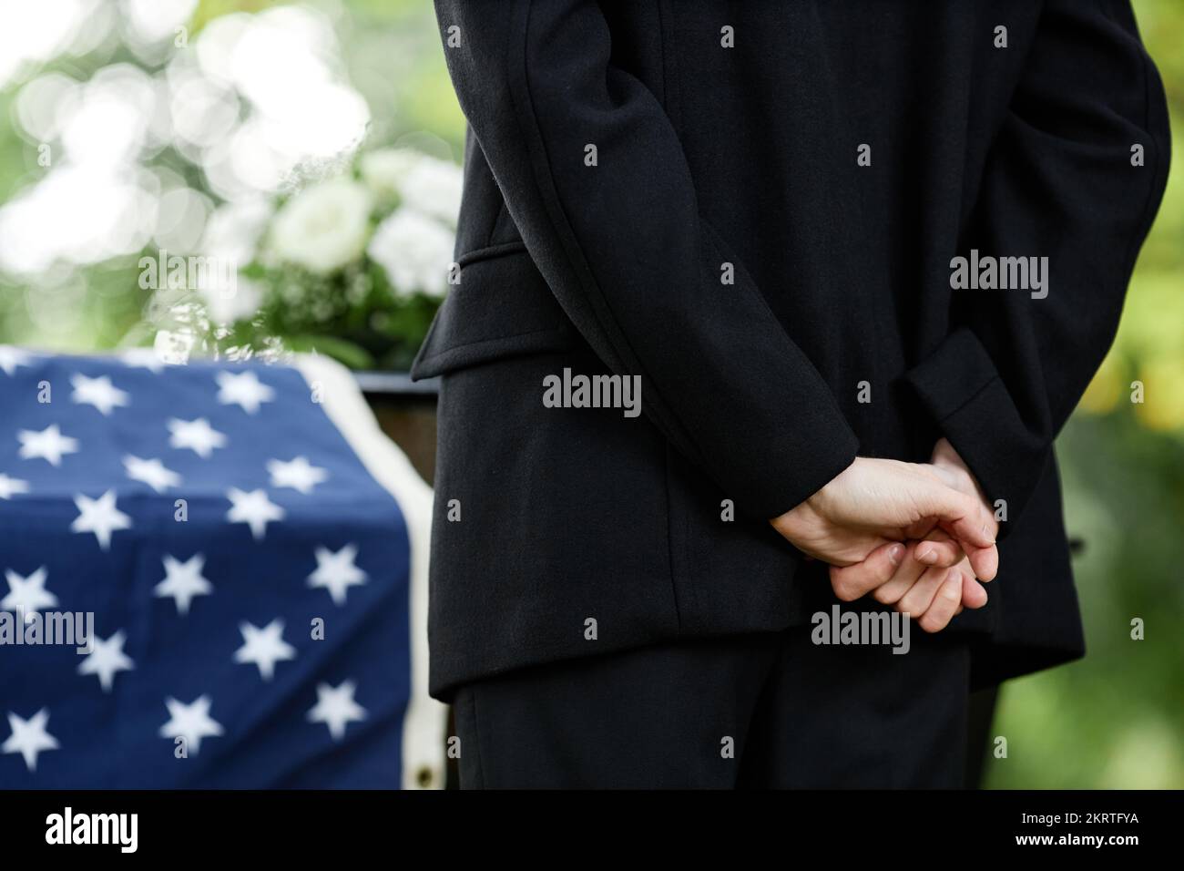 Closeup of woman wearing black at outdoor funeral ceremony clasping ...