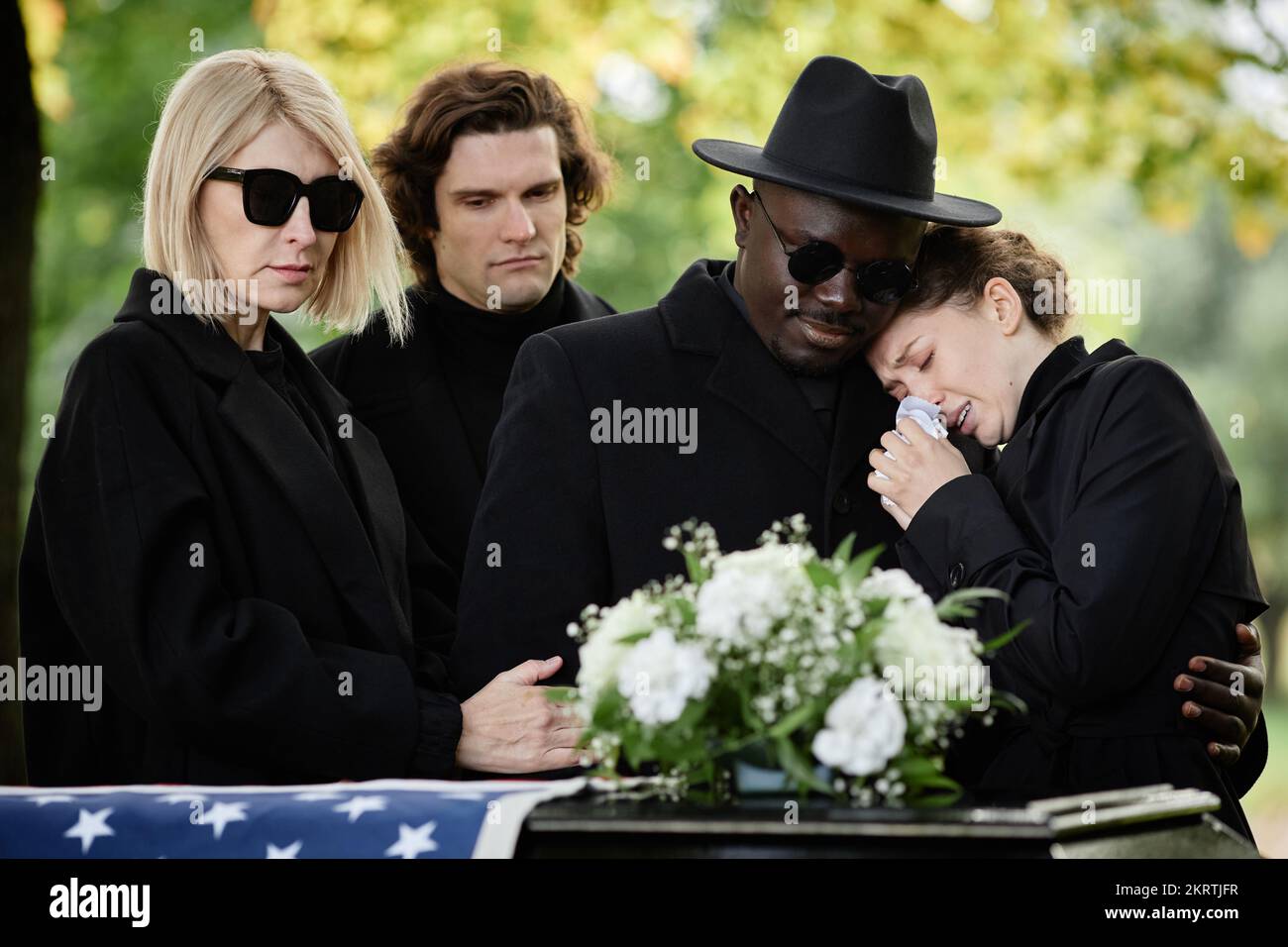 Portrait of woman crying at outdoor funeral ceremony and wearing black ...