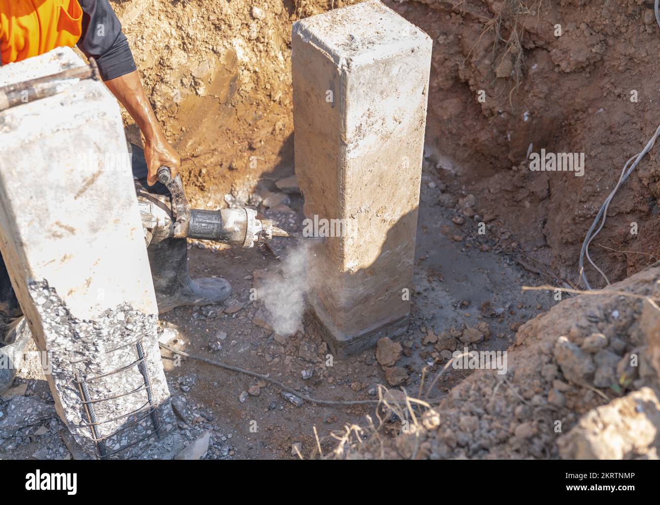 Construction worker using electric jackhammer drill to break reinforced ...