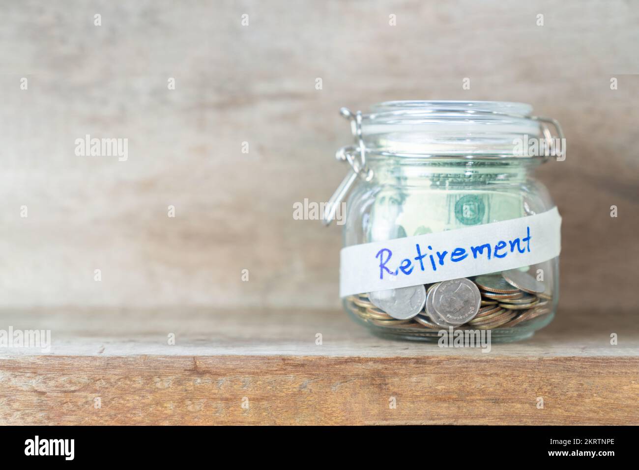 Coins and dollar bills in glass jar with retirement label for money ...