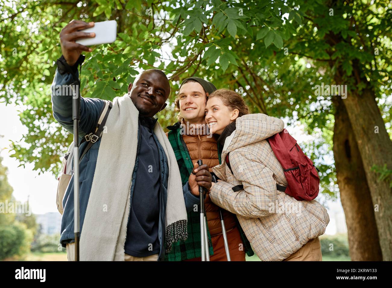 Group of smiling friends taking selfie in nature while enjoying hike ...