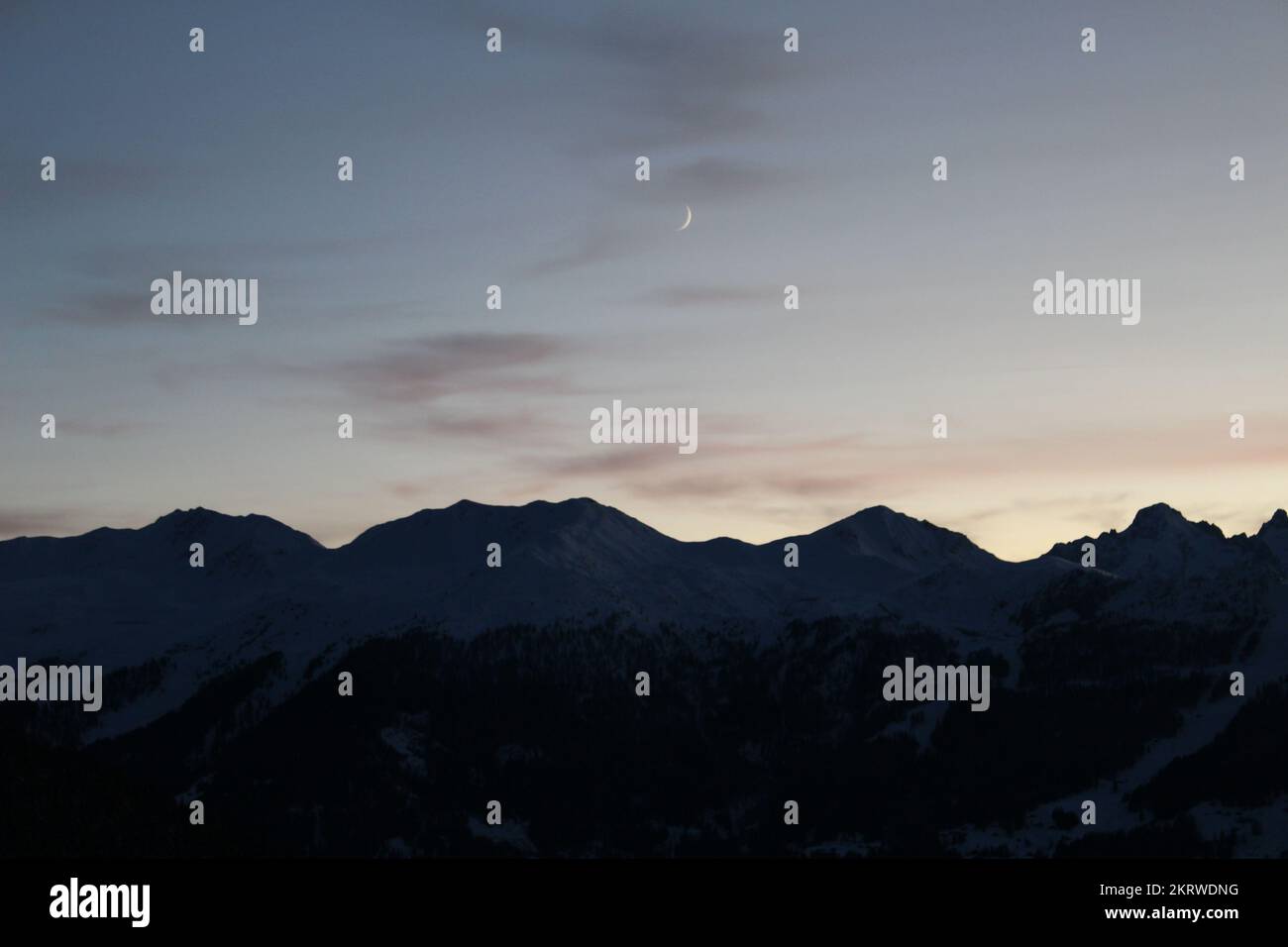 crescent moon over silhouetted swiss alps at twilight Stock Photo - Alamy