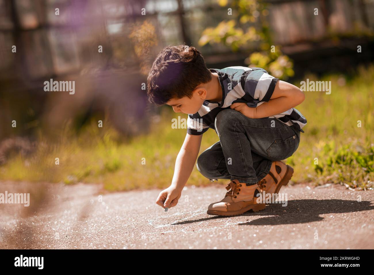 Boy drawing something on the ground Stock Photo - Alamy