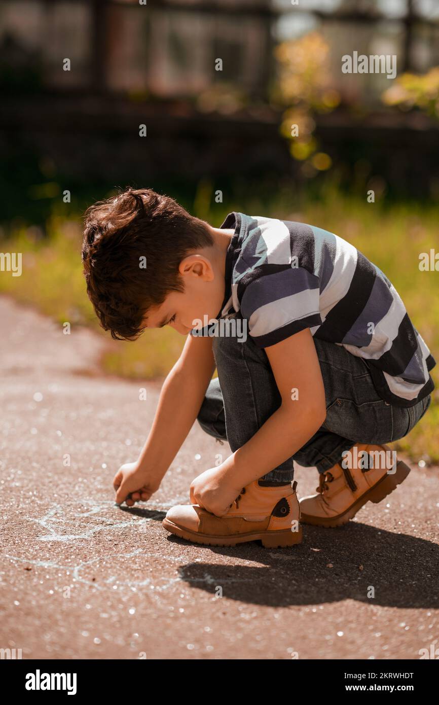 Boy drawing something on the ground Stock Photo - Alamy