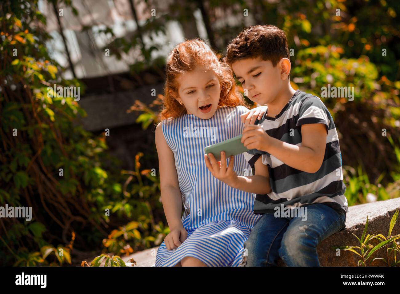Two kids sitting together and watching something online Stock Photo - Alamy