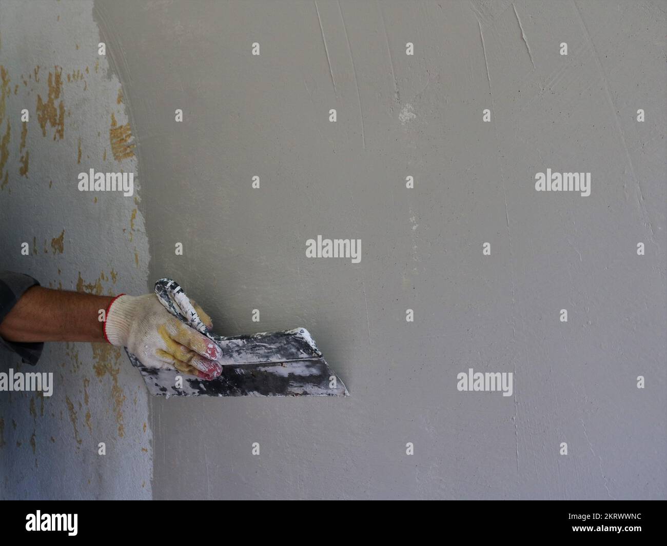 finishing leveling the surface of the room wall using a wide spatula ...