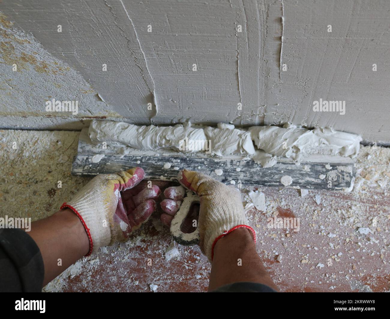 applying putty on the wall with a wide spatula, leveling the wall with ...