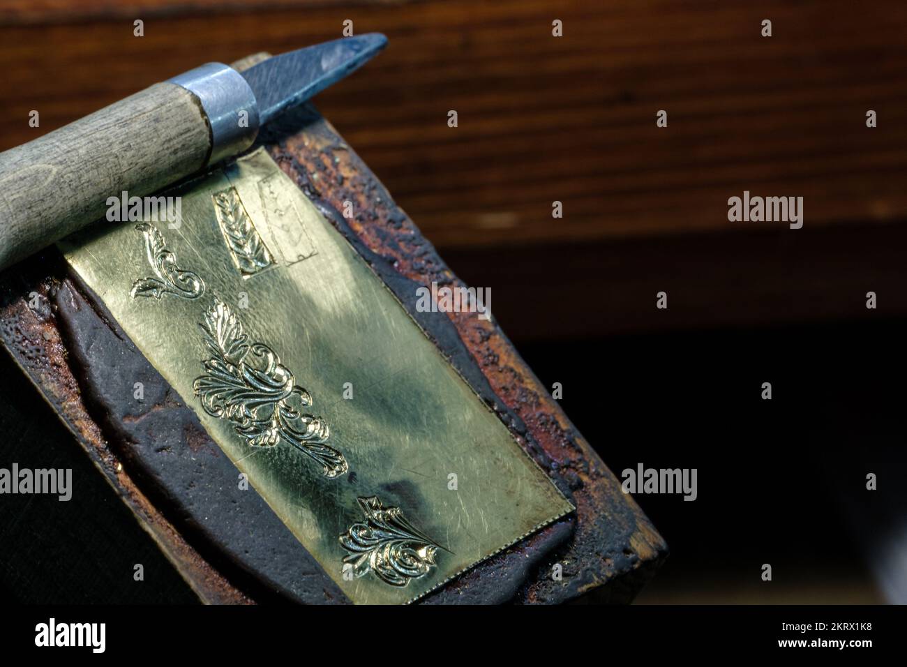 Handmade gold watch blanks on wooden table, metal engraving tools ...