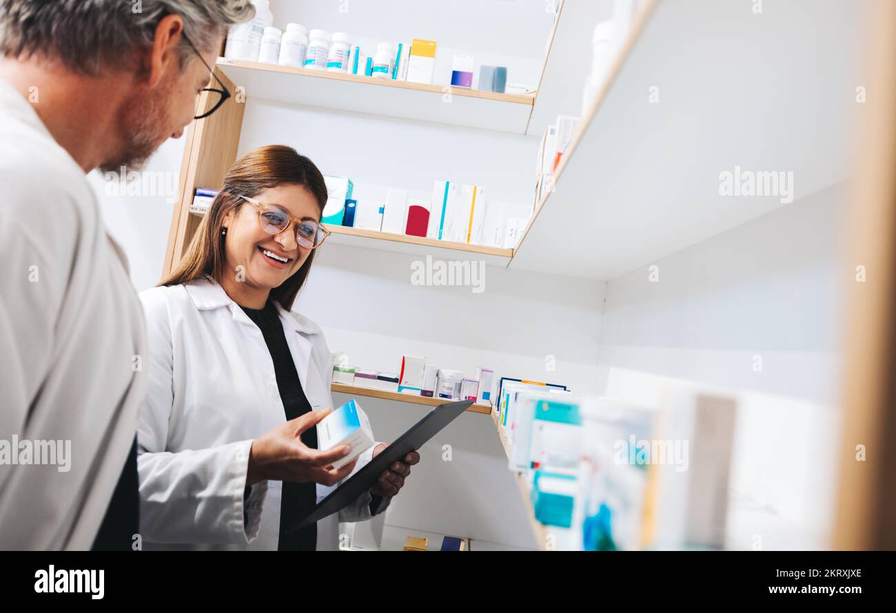 Pharmacists picking medication from a shelf in a chemist. Two mature ...