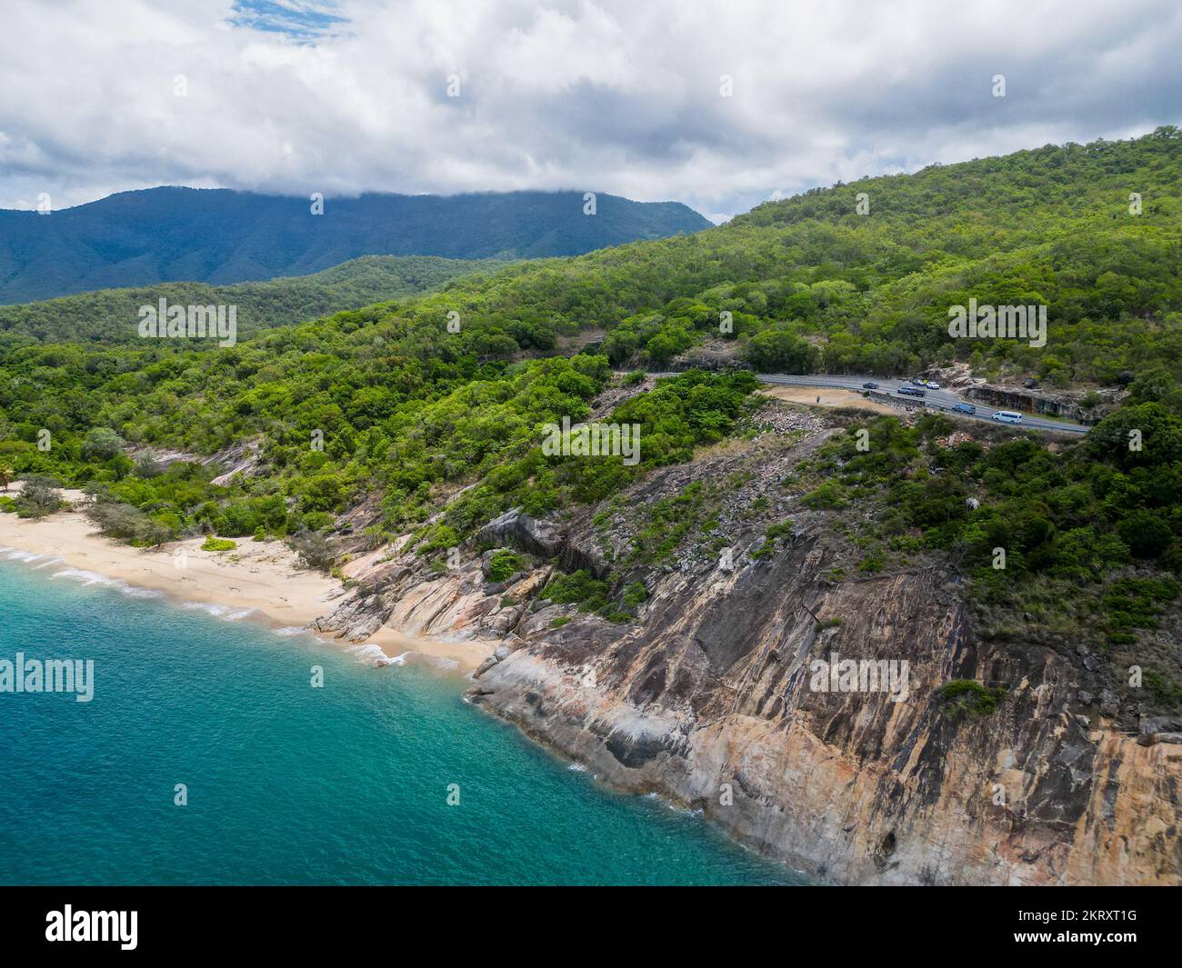 Aerial view of tropical road alongside beautiful blue water and sandy ...