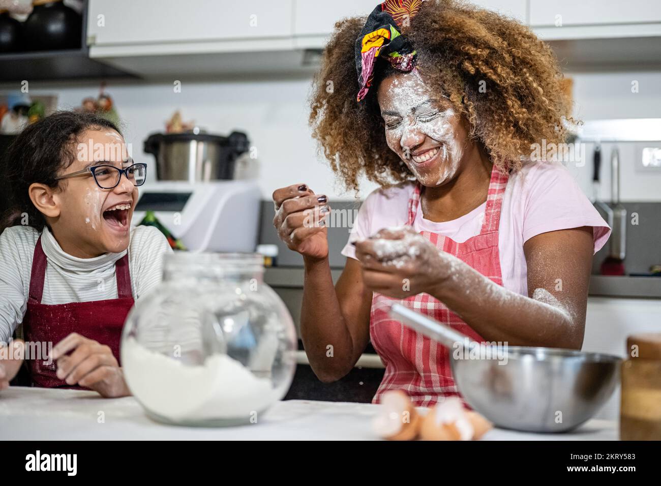 Mom and daughter play with flour while preparing sweets at home ...