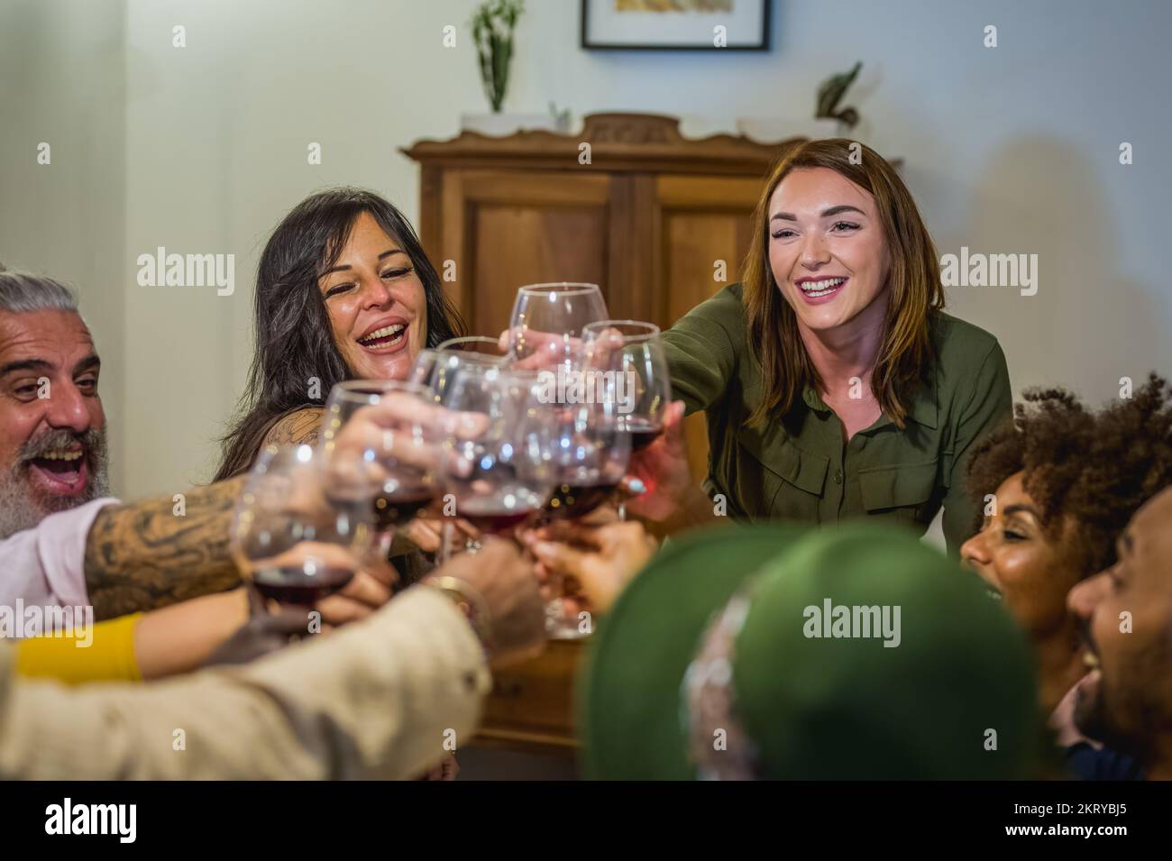 Mixed age range group of friends toasting at dinner party, focus on ...