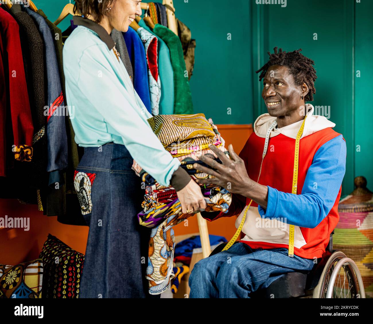 two tailors in their shop workshop passing fabrics to create clothes ...