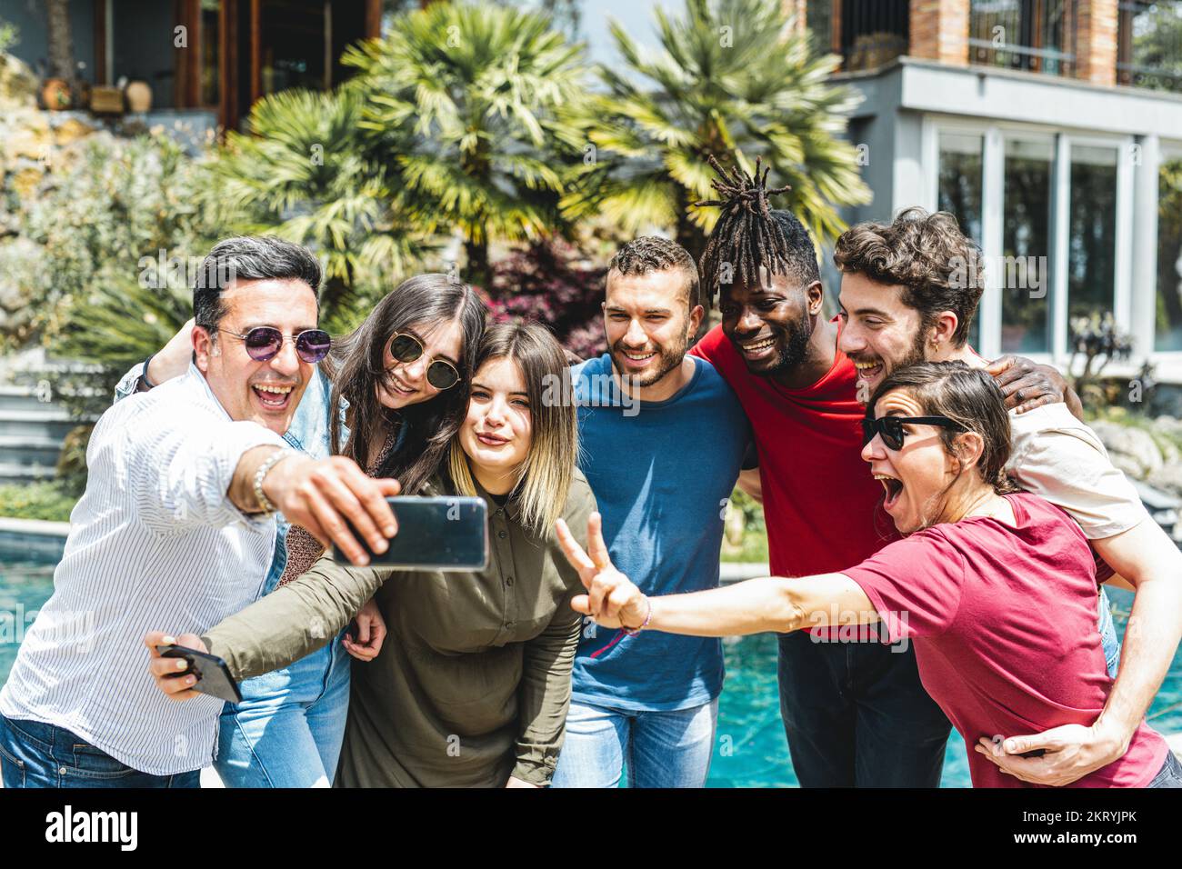 Group of mixed age range friends taking selfy in the garden of the ...