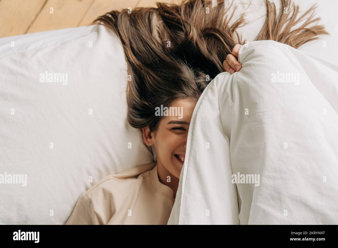 Young cheerful playful brunette woman with long hair hides her face ...