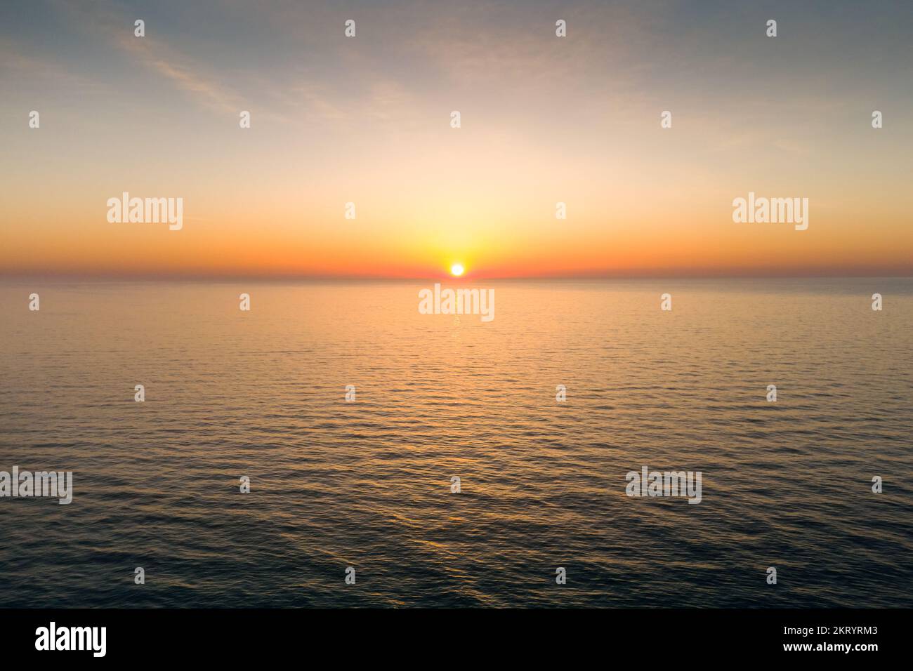 The sun casts golden light out over a body of water at dawn Stock Photo ...