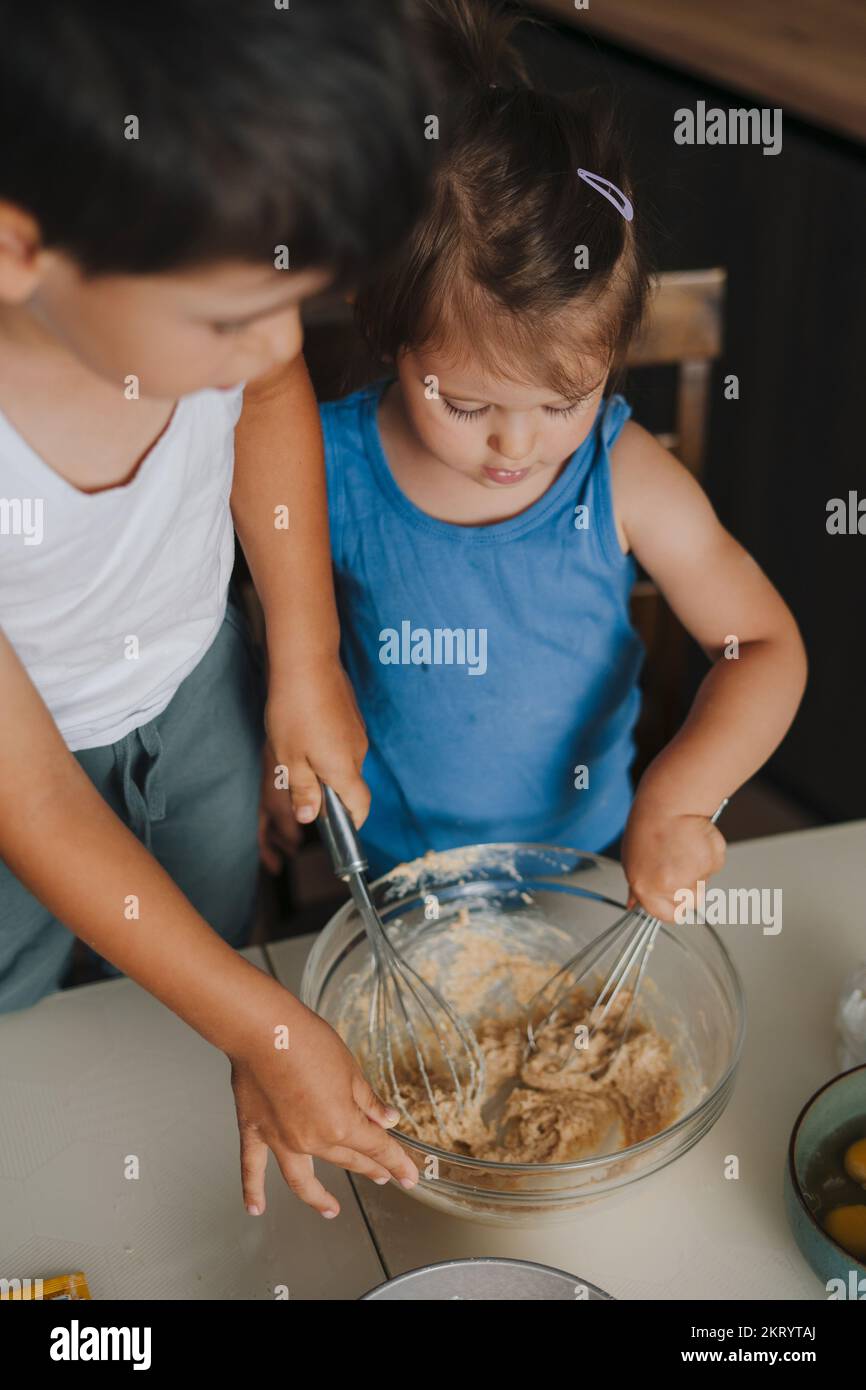 Funny two little kids helper mixing ingredients, making dough helping ...