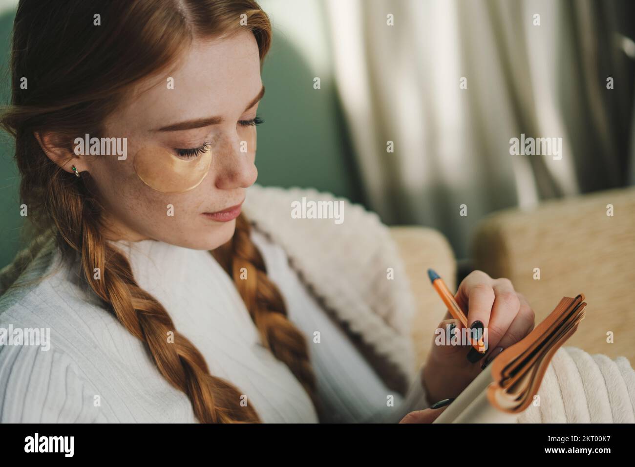 Young attractive woman with eyepatches making face care morning routine ...