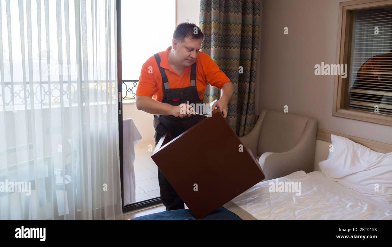 A working man assembles coffee table. Hotel worker screwing the leg to ...