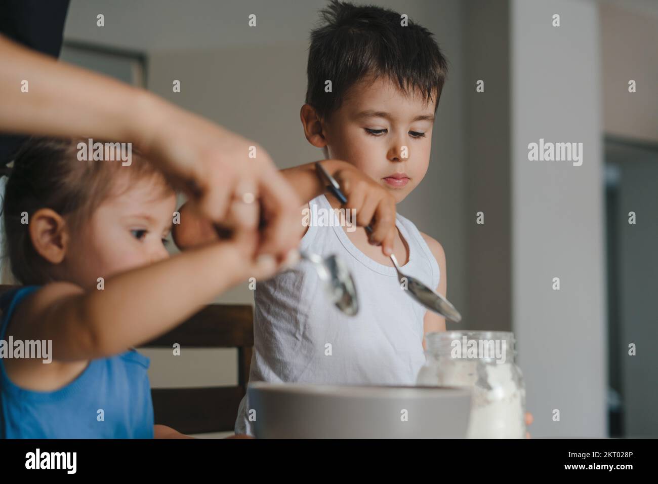 Family with adorable two little kids cooking in modern kitchen pancakes ...