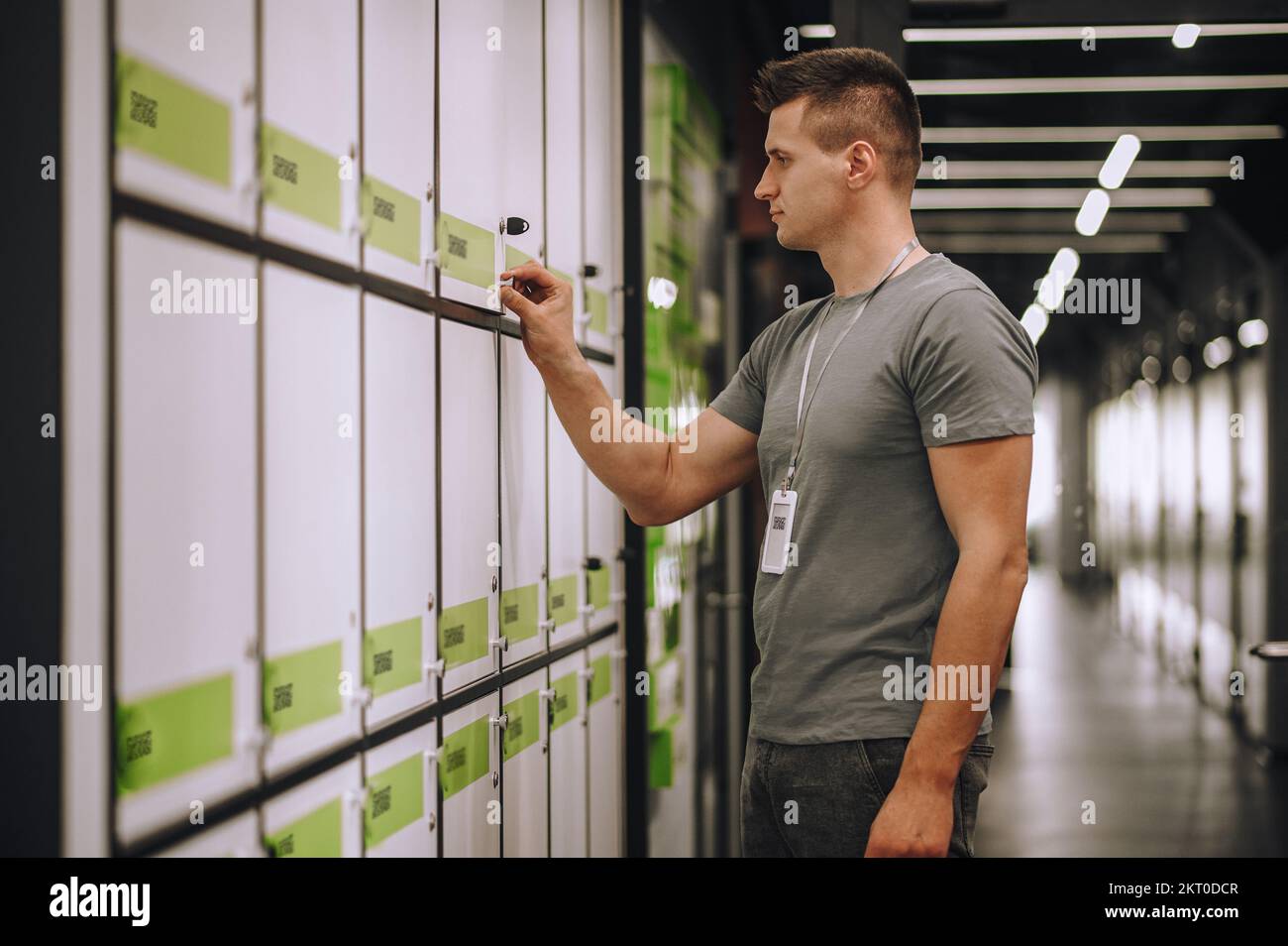 Man standing sideways to camera opening locker Stock Photo - Alamy
