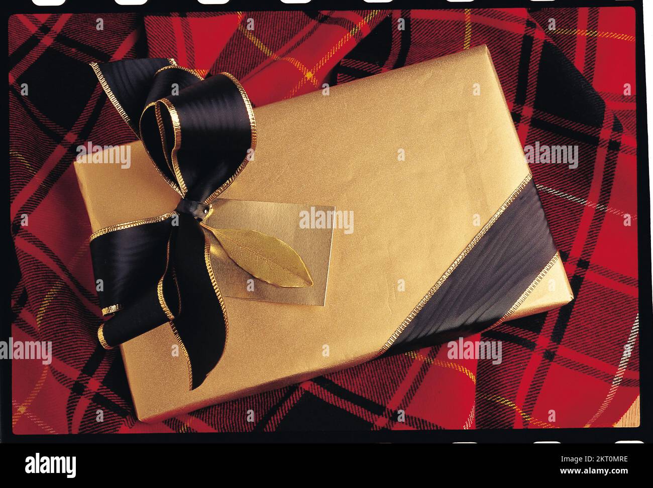 A gold present tied with a black ribbon Stock Photo - Alamy