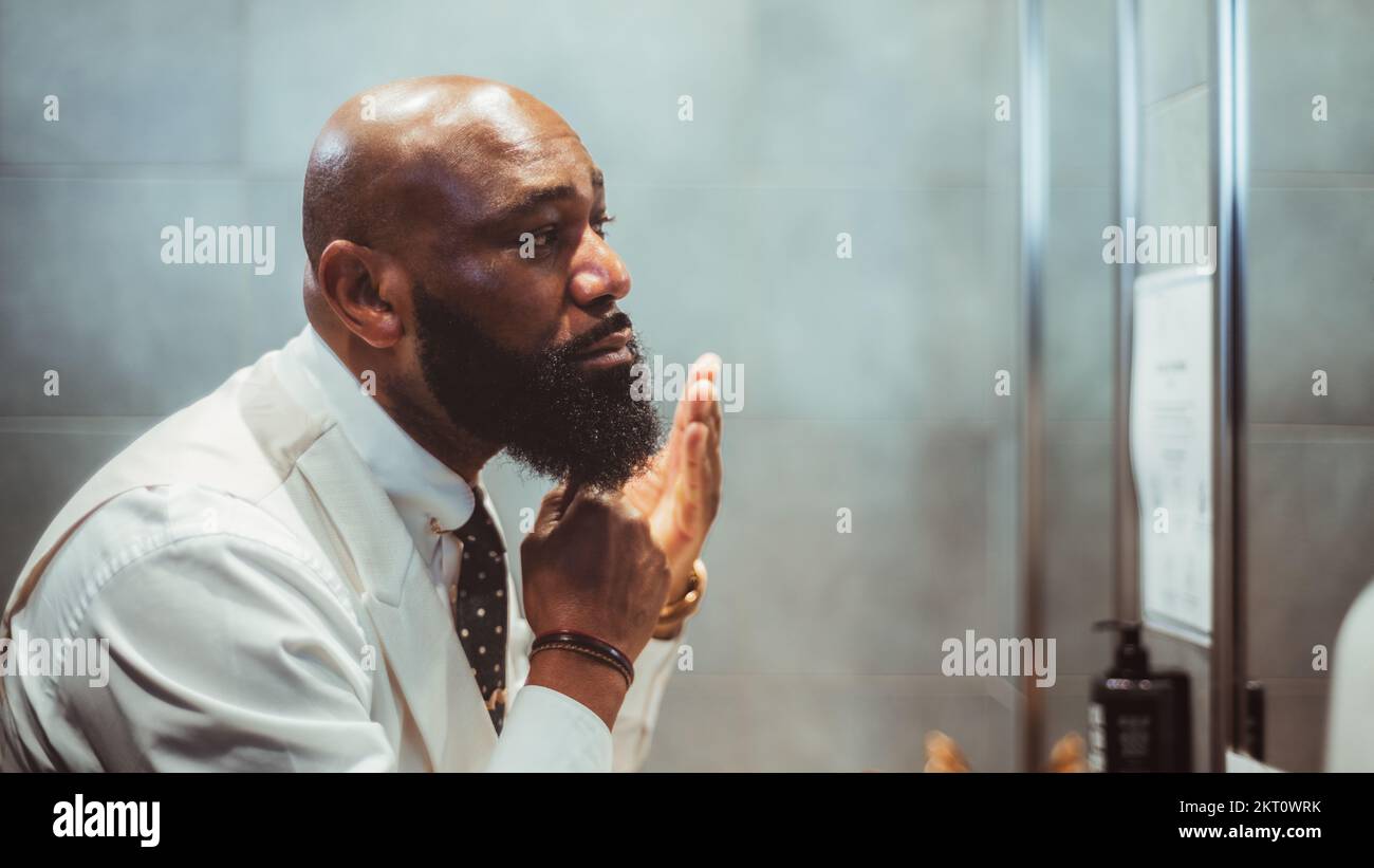 A profile view of a handsome bald black man grooming, brushing, and ...