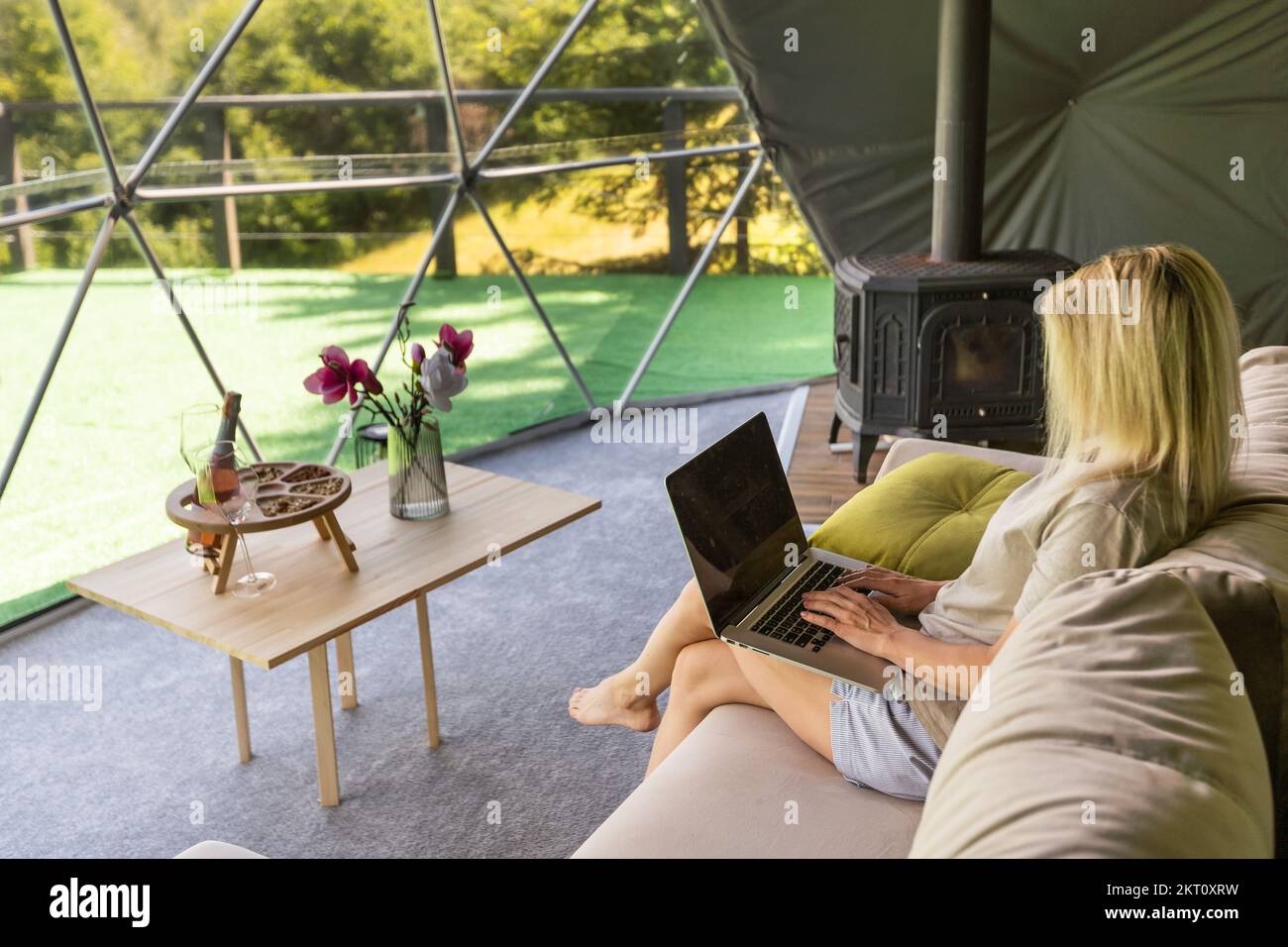 Woman working on laptop geo dome tents. Green, blue background. Cozy, camping, glamping, holiday ...
