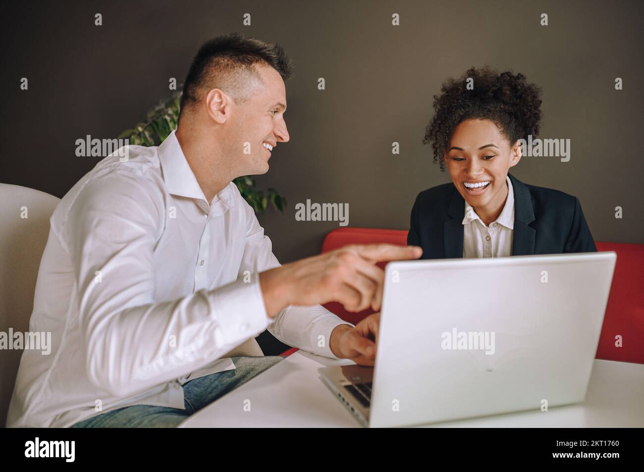 Man showing laptop screen to laughing woman Stock Photo - Alamy