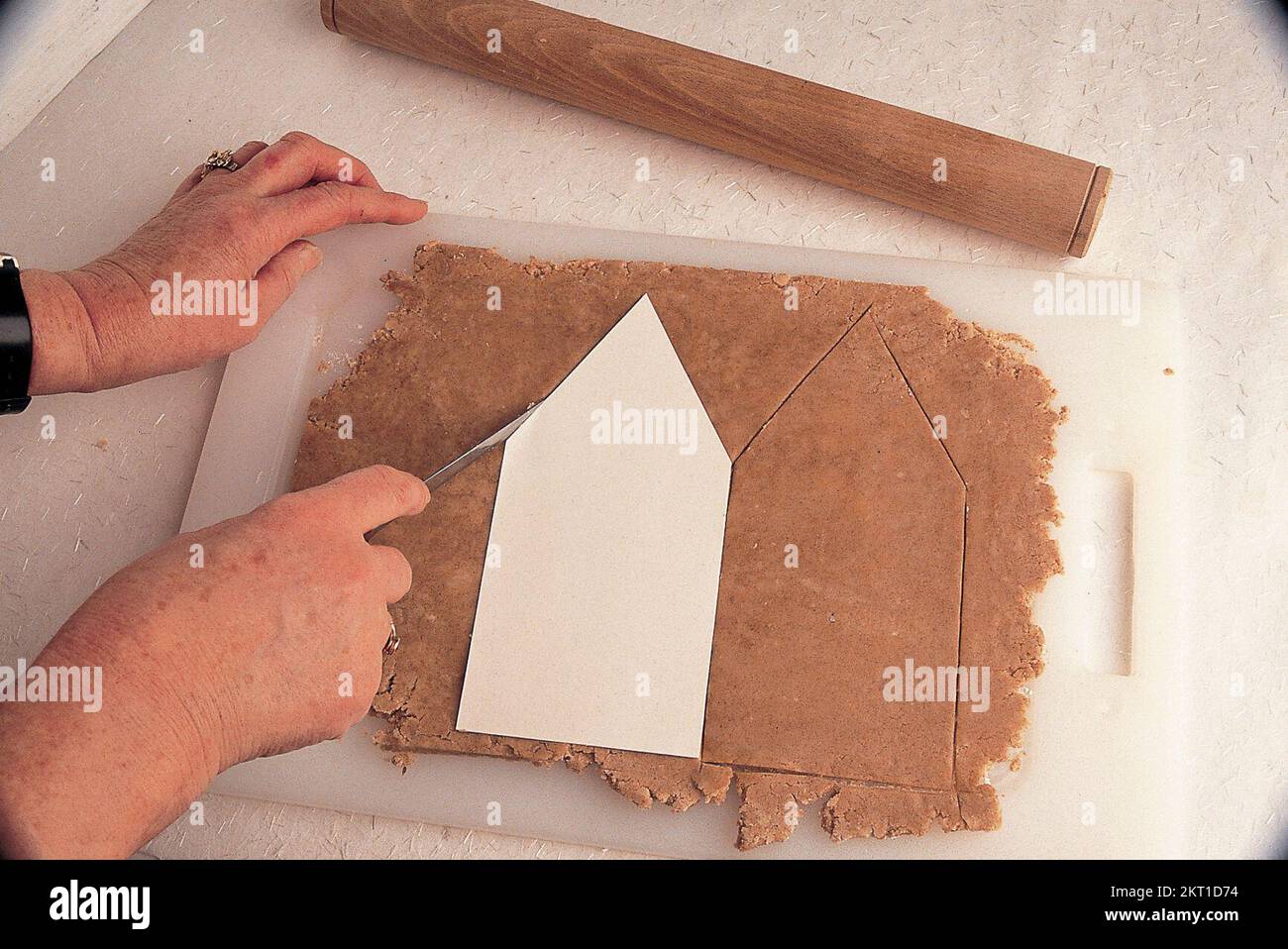 Cutting around the house template on the dough Stock Photo - Alamy