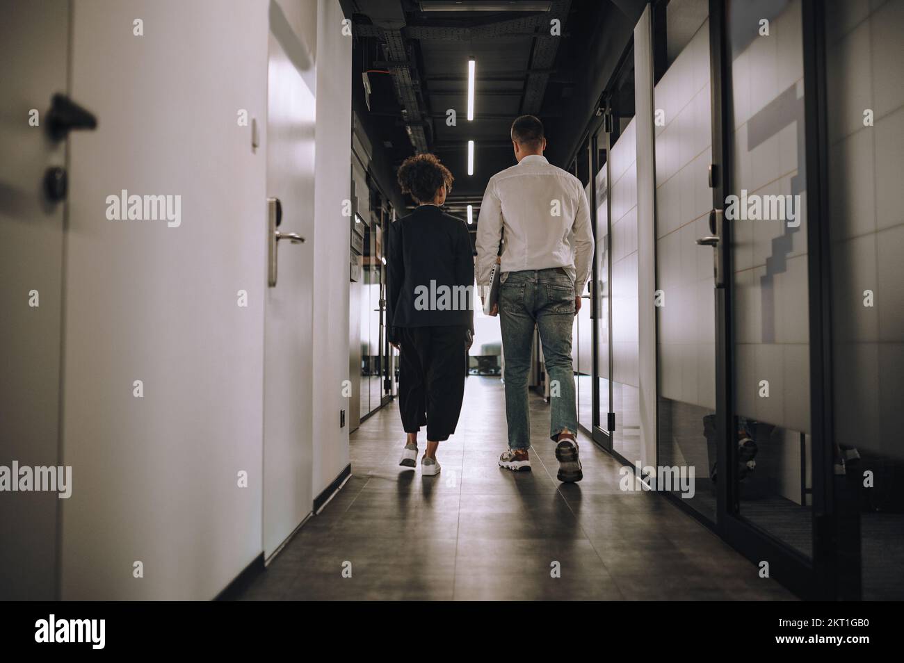 Back view of man and woman walking office corridor Stock Photo - Alamy