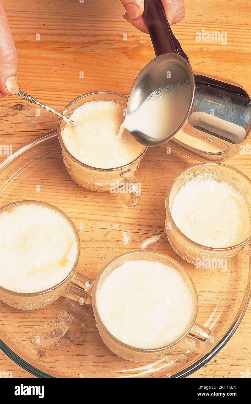 Pouring hot milk into each glass using a ladle Stock Photo - Alamy