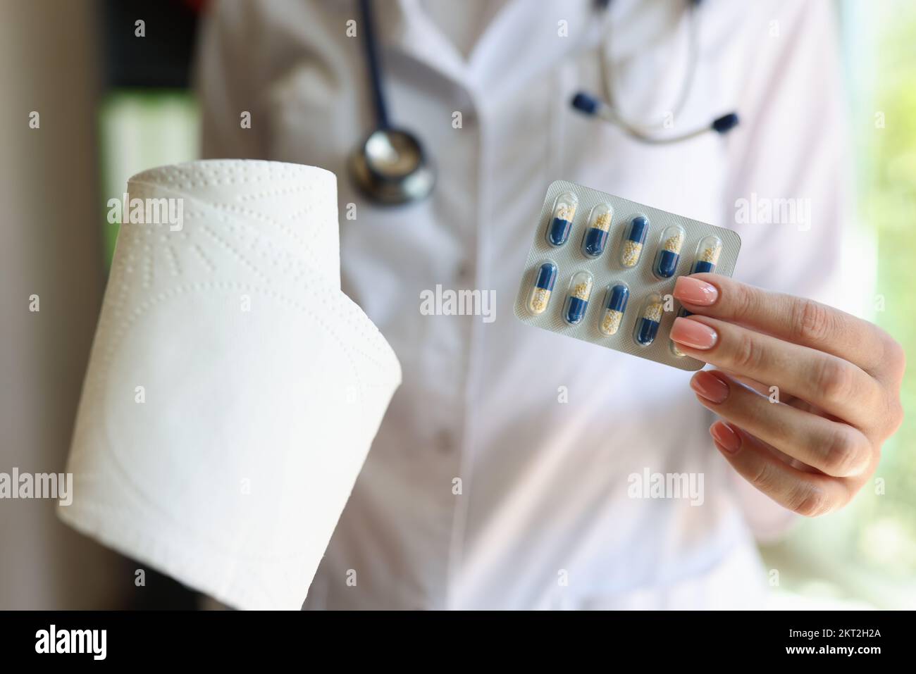 Doctor is holding roll of toilet paper and pack of capsules close-up ...
