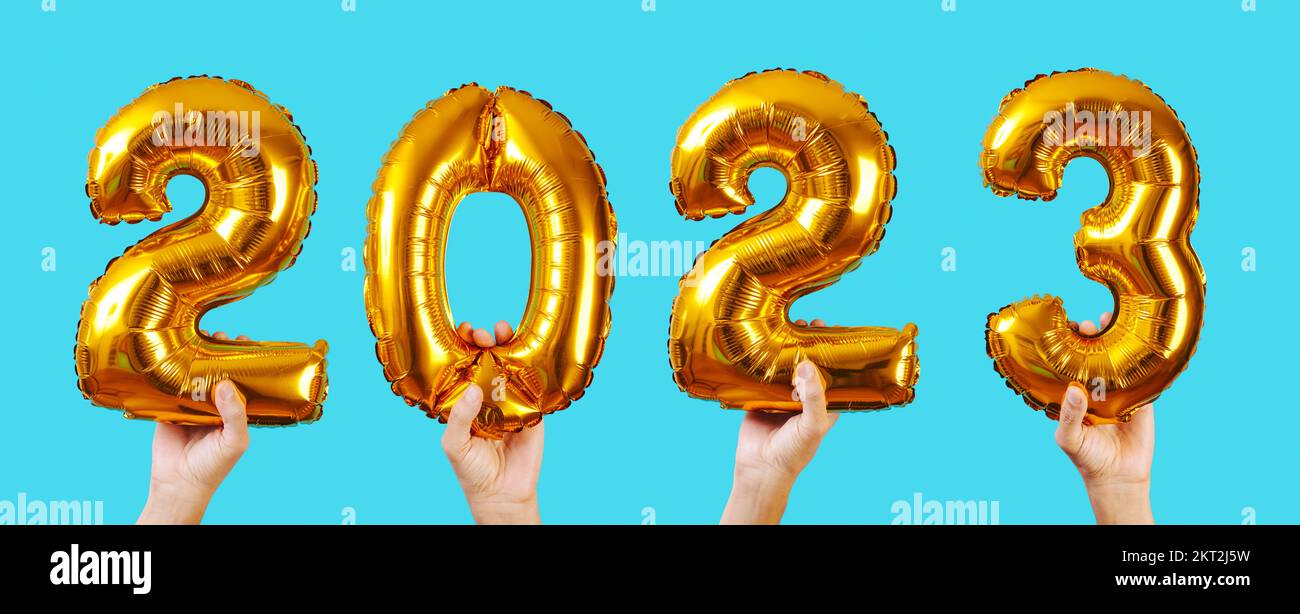 hands holding some golden number-shaped balloons forming the number ...