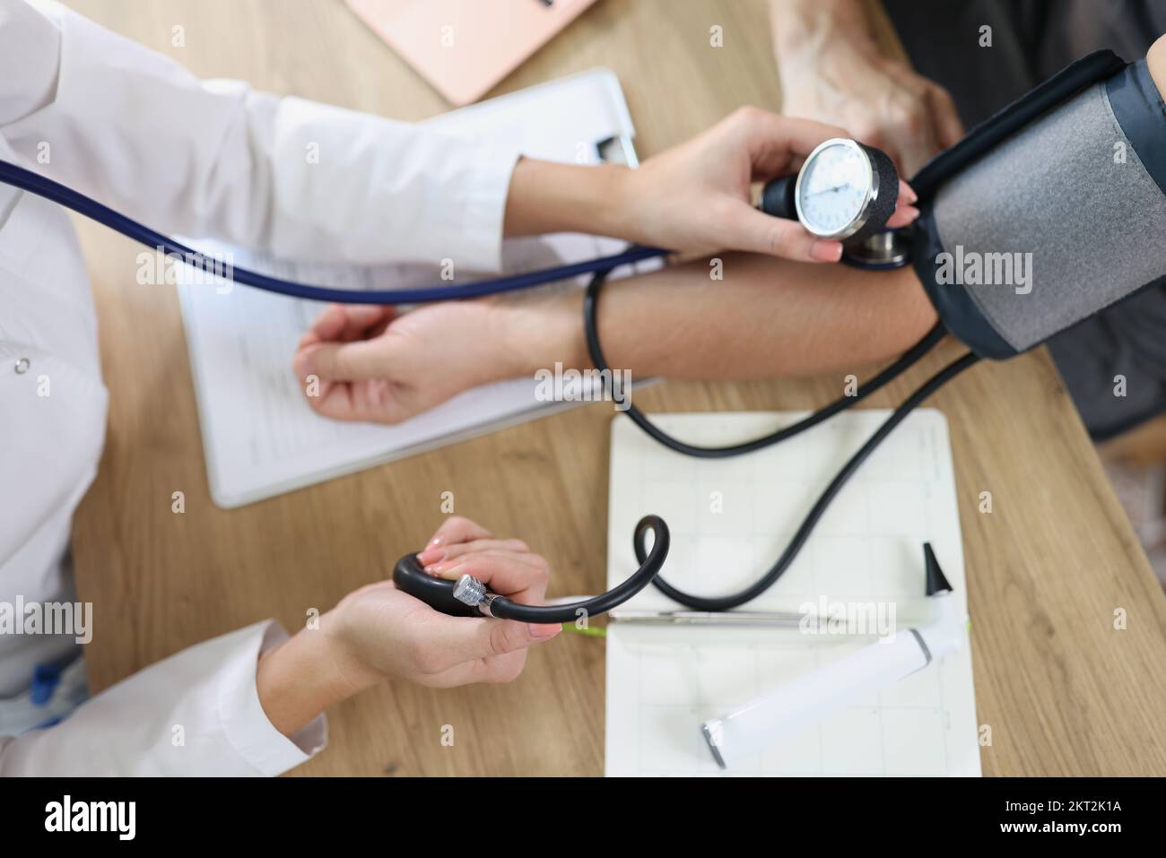 Female doctor using sphygmomanometer checks patient's blood pressure in ...